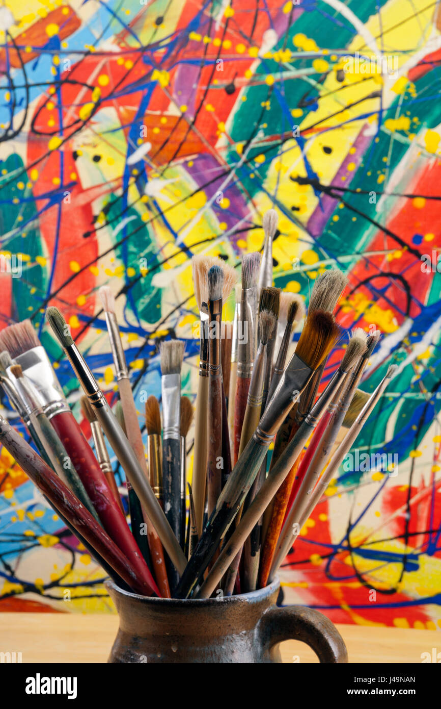 A collection of well used art paint brushes with a highly colourful ...