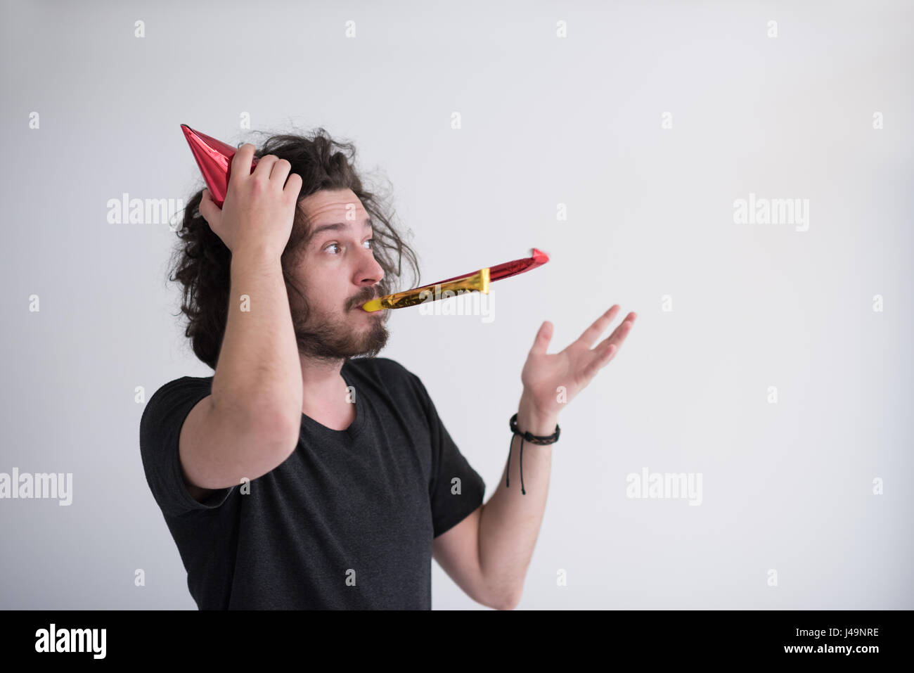 Portrait of a man in party hat blowing in whistle isolated on a white ...