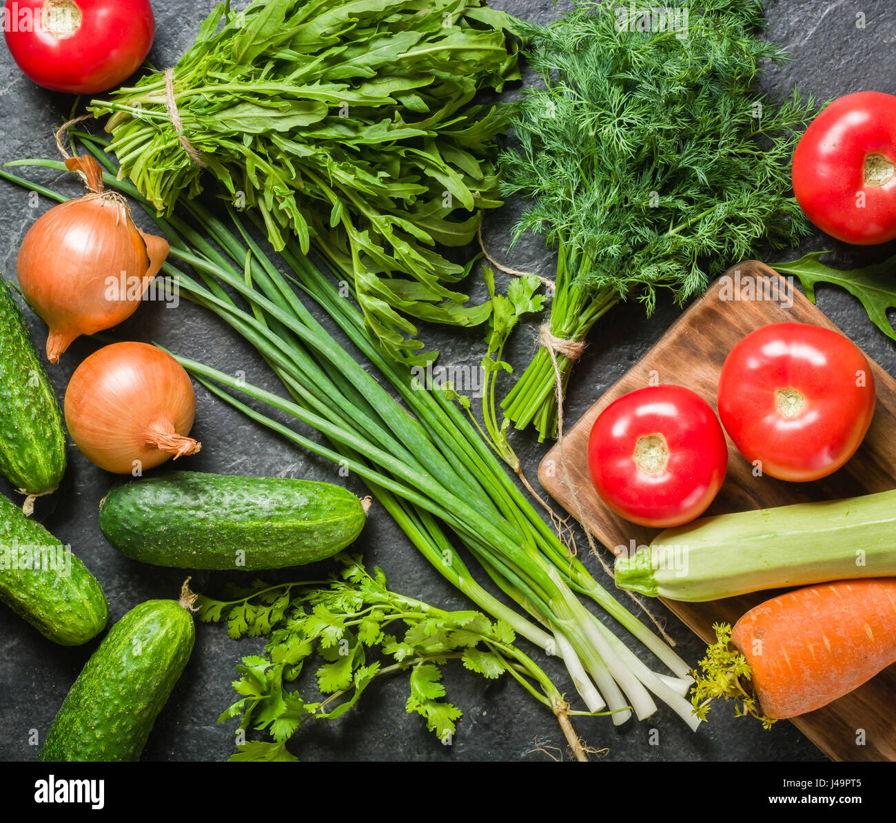 Fresh vegetables and greens in bunches arranged in a frame on a black ...