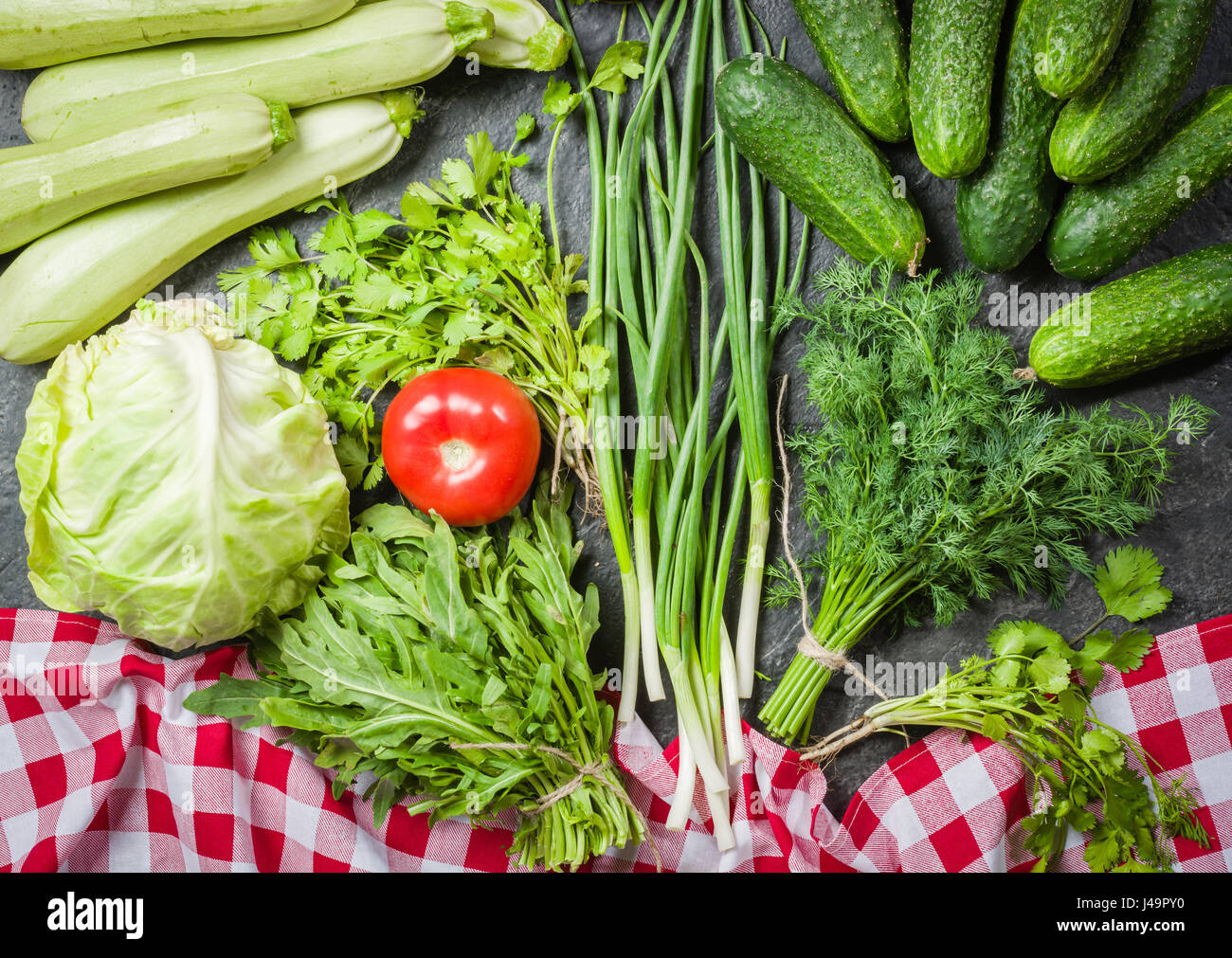 Fresh vegetables and greens in bunches arranged in a frame on a black ...