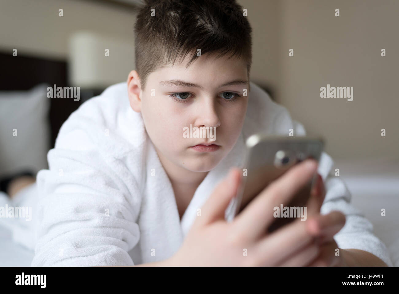 Boy in bathrobe writes sms on phone in hotel room Stock Photo - Alamy