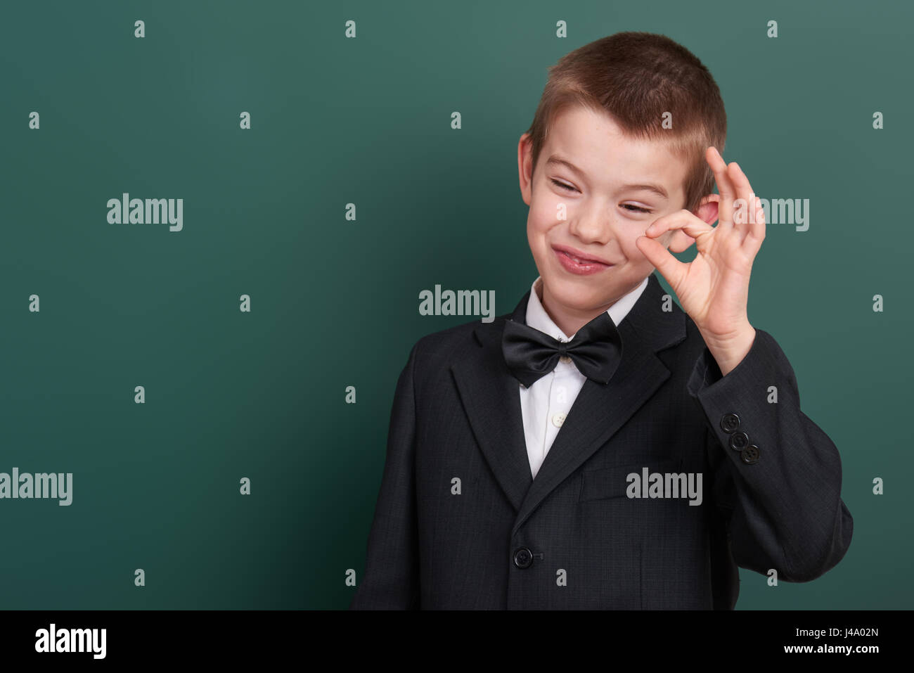 school boy show ok sign, portrait near green blank chalkboard ...