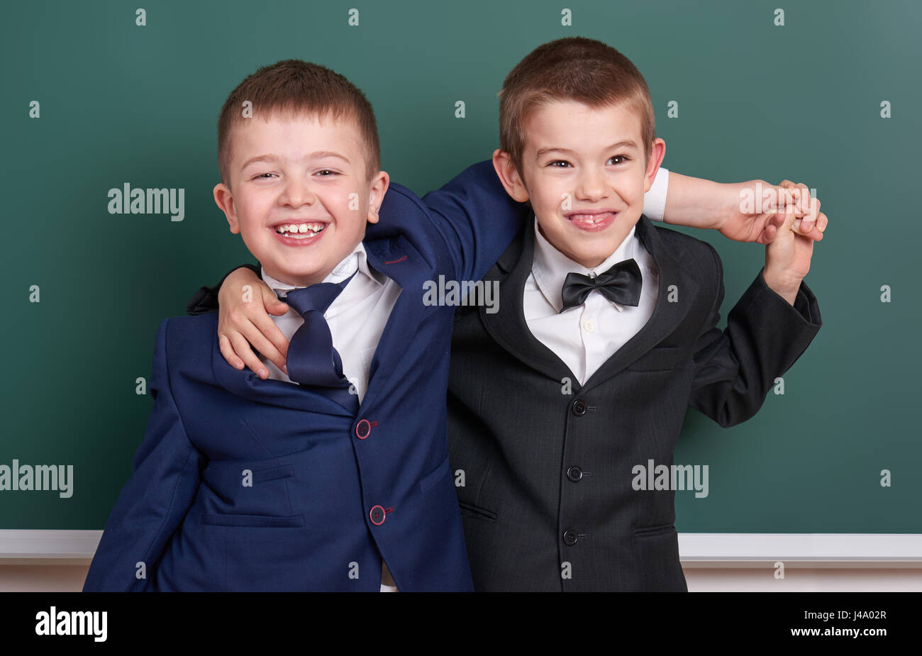 two friends, elementary school boy near blank chalkboard background ...