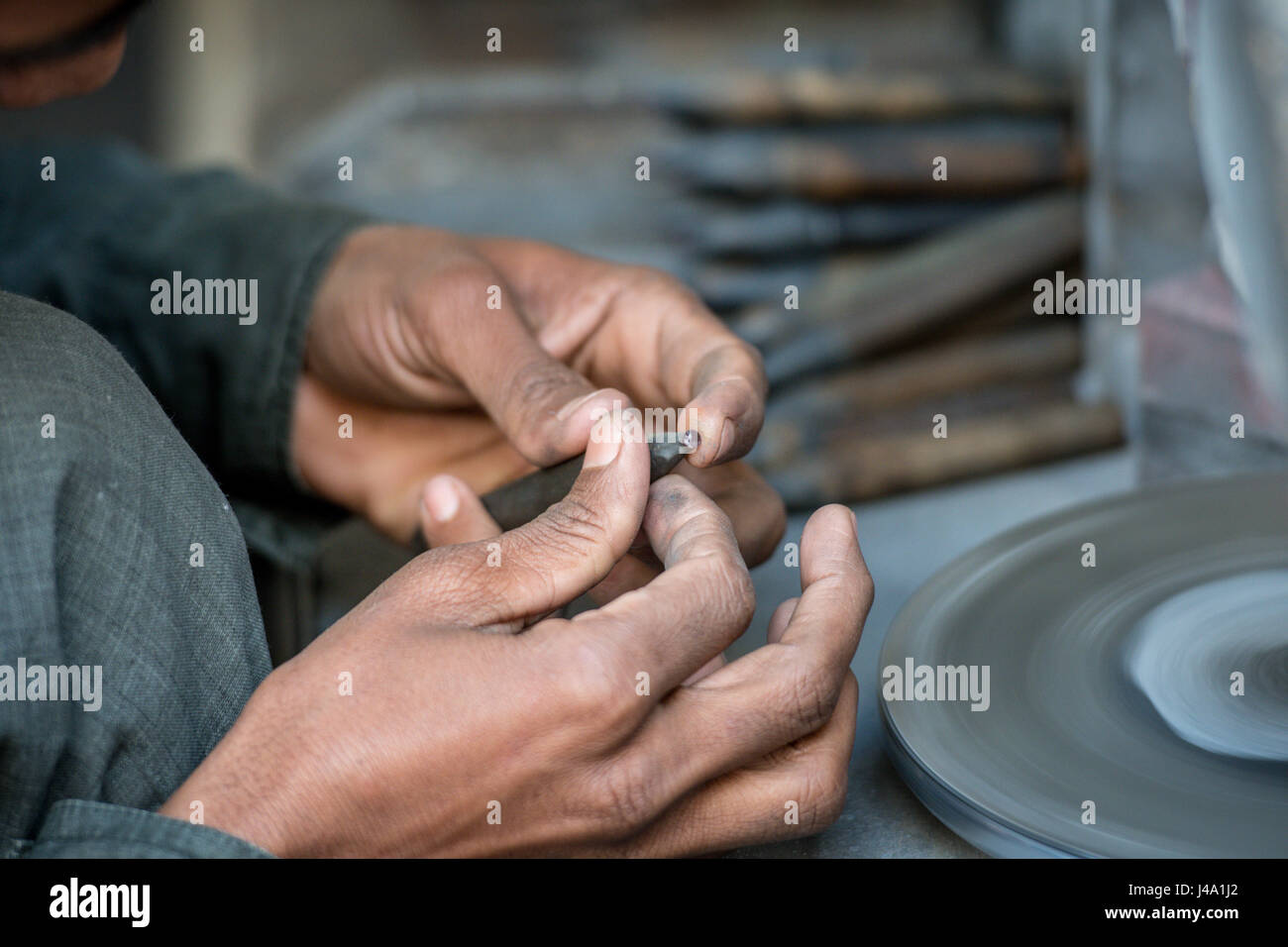 Close up of Indian mans hands typing on laptop with folders and mug ...