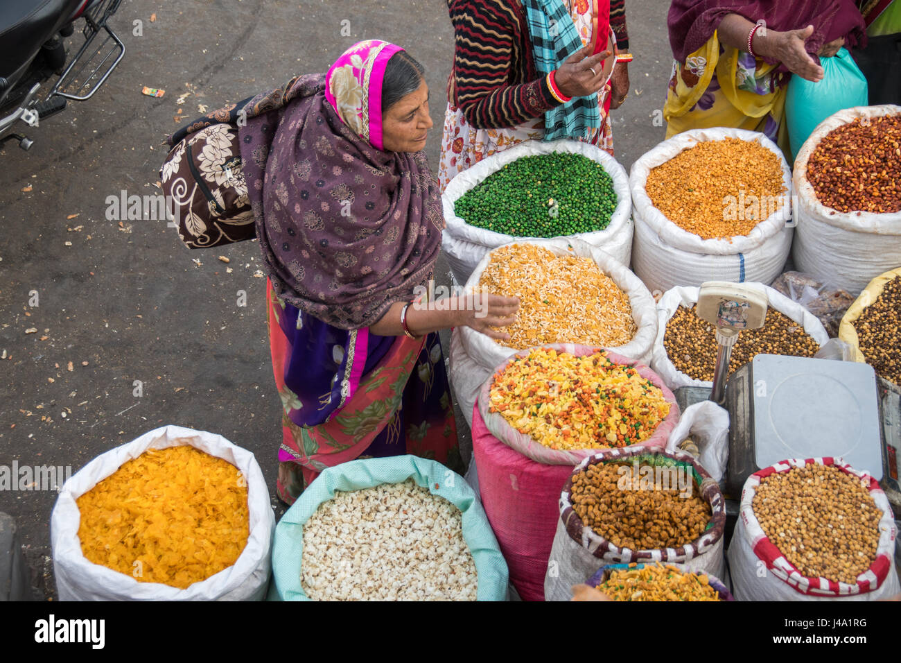 Indian woman sorting through grains being sold at an open market in ...