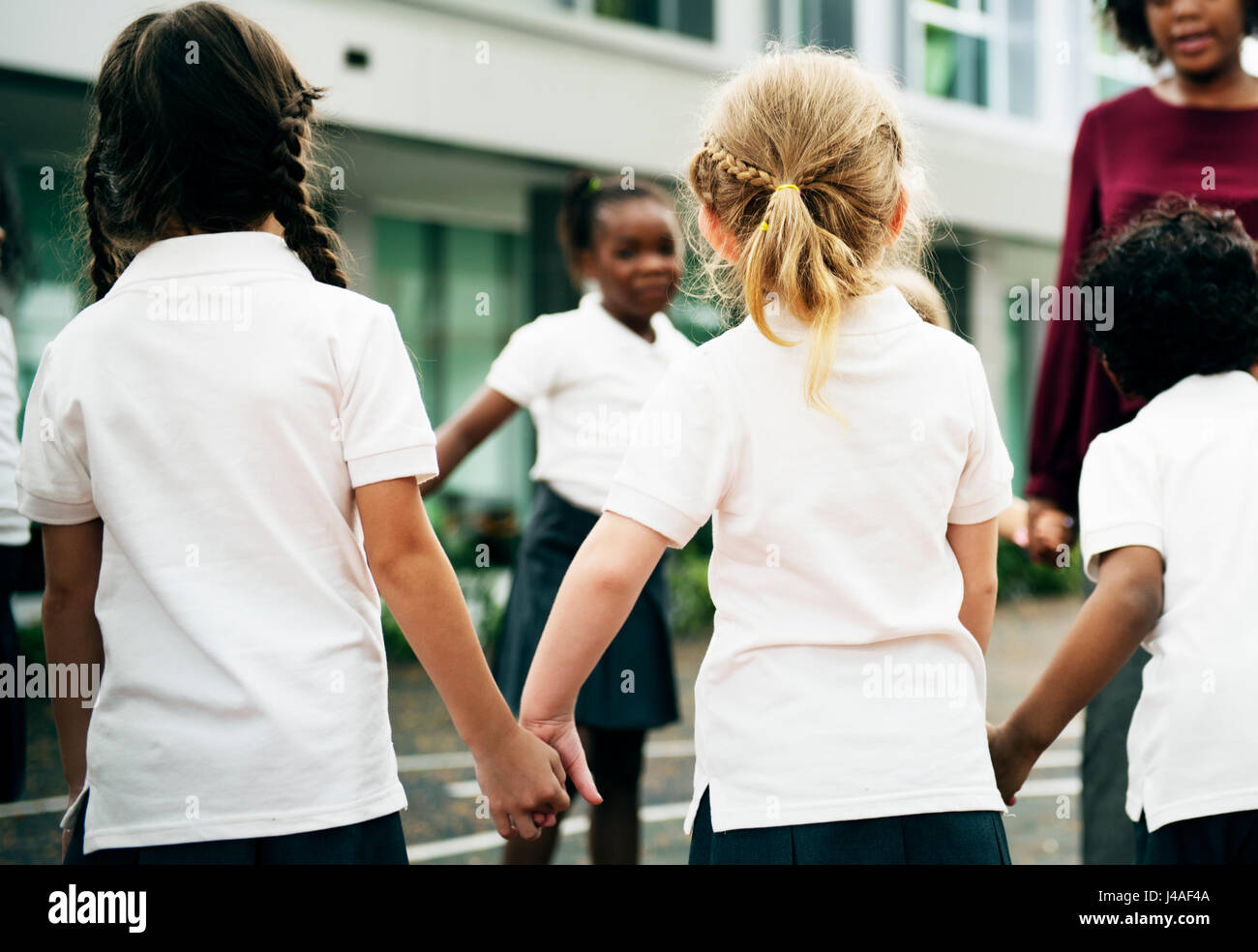 Group of diverse kindergarten students standing holding hands together ...