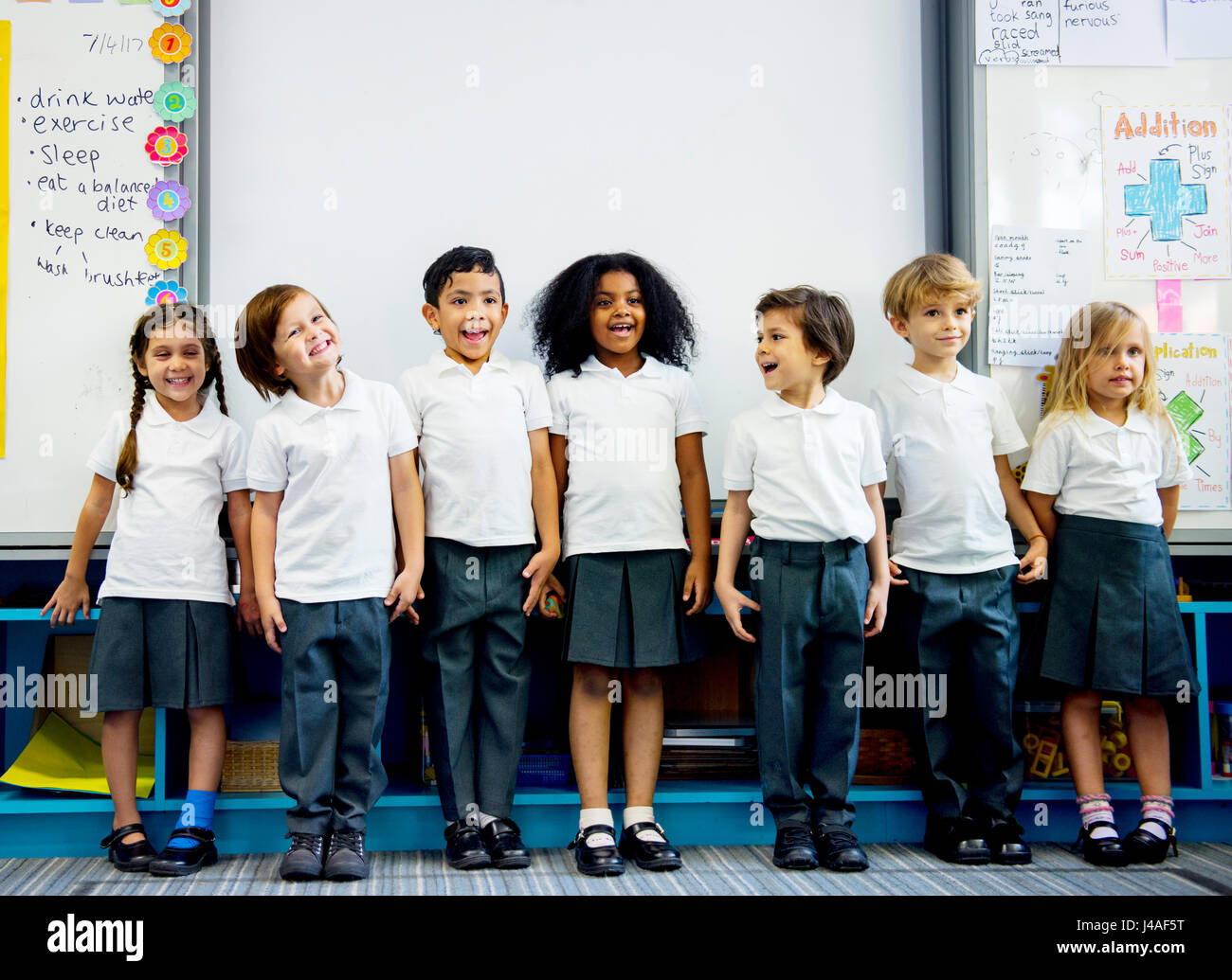 Group of diverse kindergarten students standing together in classroom ...