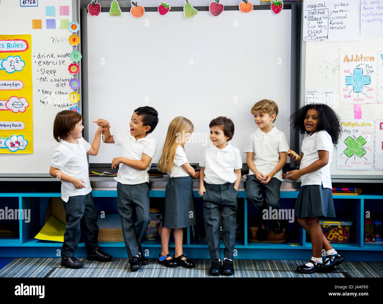 Group of diverse kindergarten students standing together in classroom ...