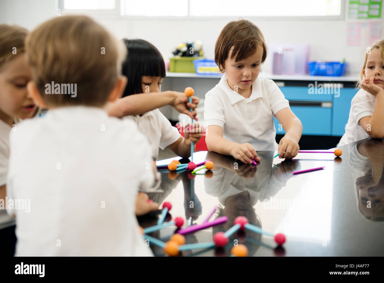 Diverse kindergarten students holding learning structures from toys ...
