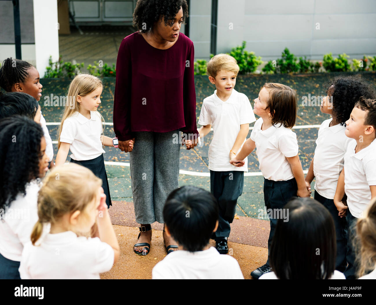 Group of diverse kindergarten students standing holding hands together ...