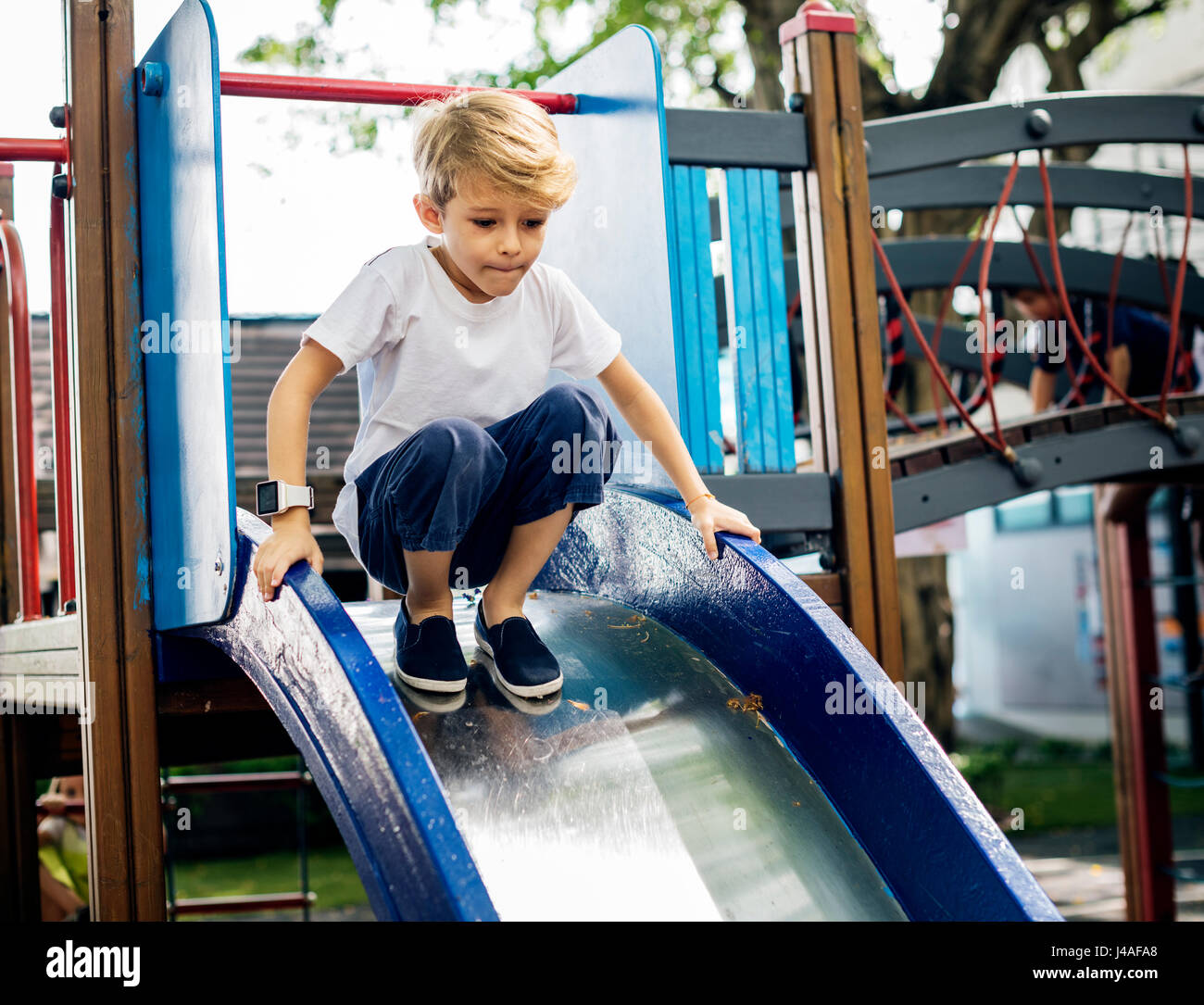 Young boy playing slide in playground Stock Photo - Alamy