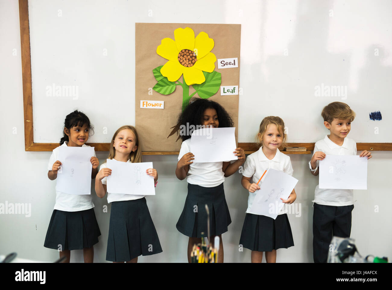 Group of diverse kindergarten students standing presenting drawing ...