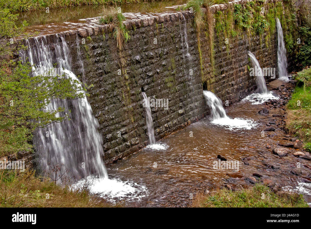 Square concrete blocks dam on the river with holes for drain water ...