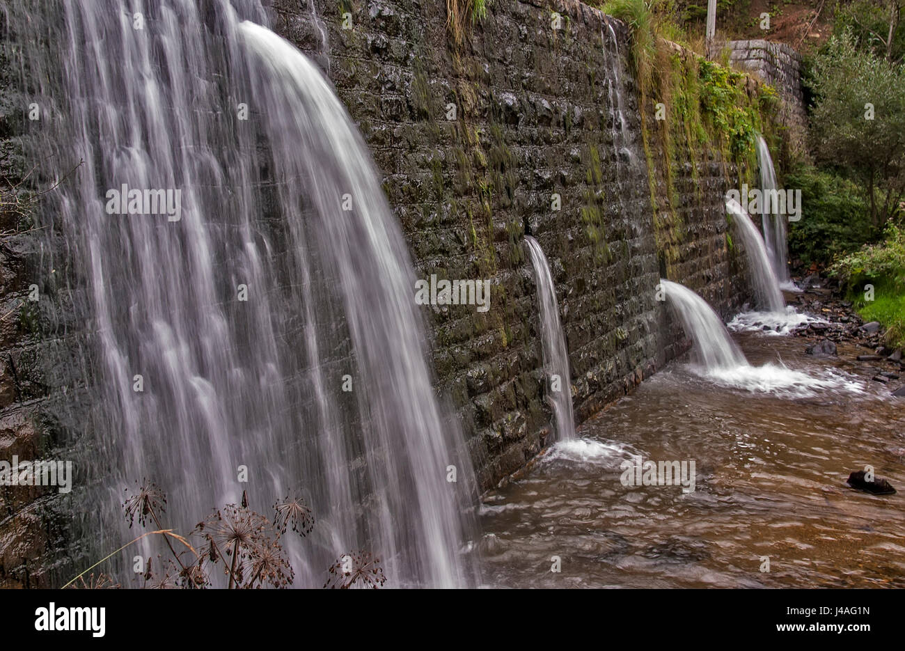 Square concrete blocks dam on the river with holes for drain water ...
