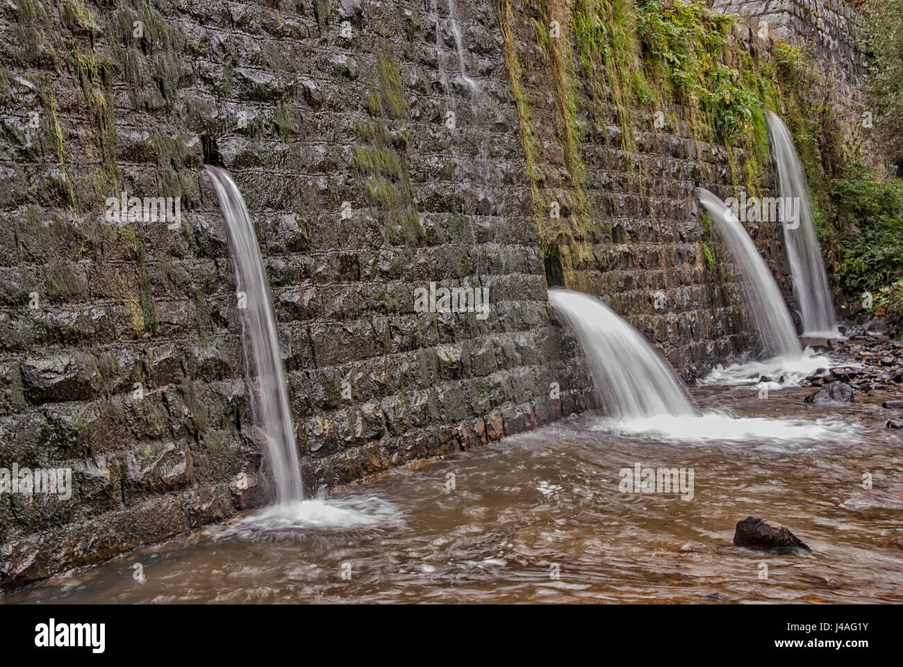 Square concrete blocks dam on the river with holes for drain water ...