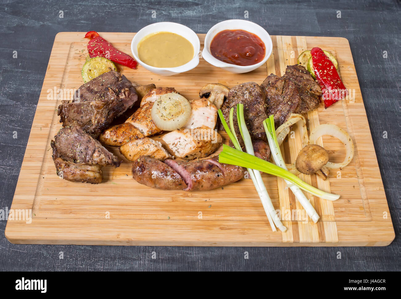 Mixed grilled meats platter with vegetables and sauces. Platter located ...