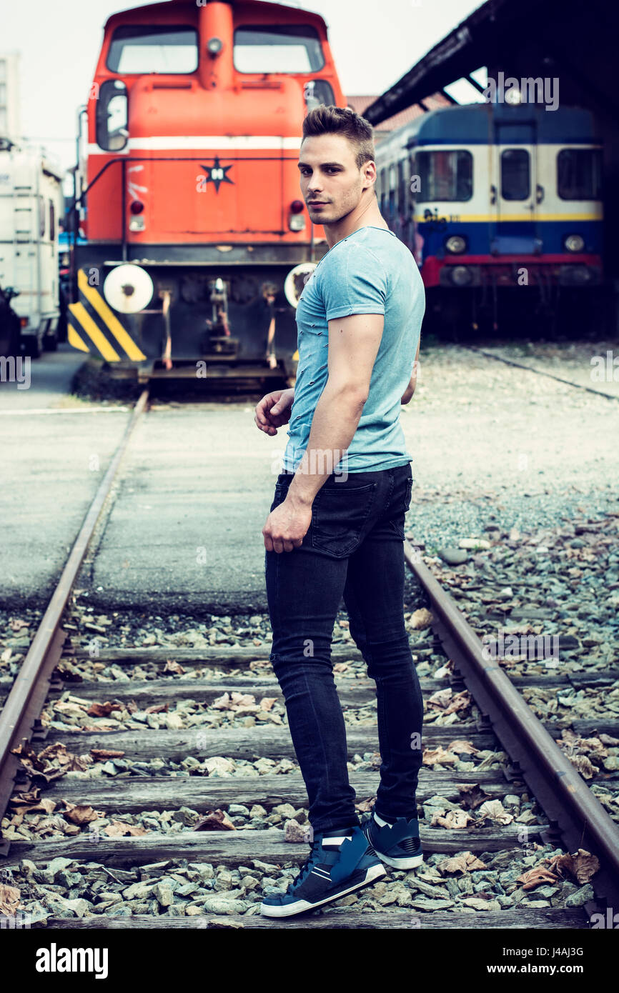 Handsome young man in front of old train, looking away Stock Photo - Alamy