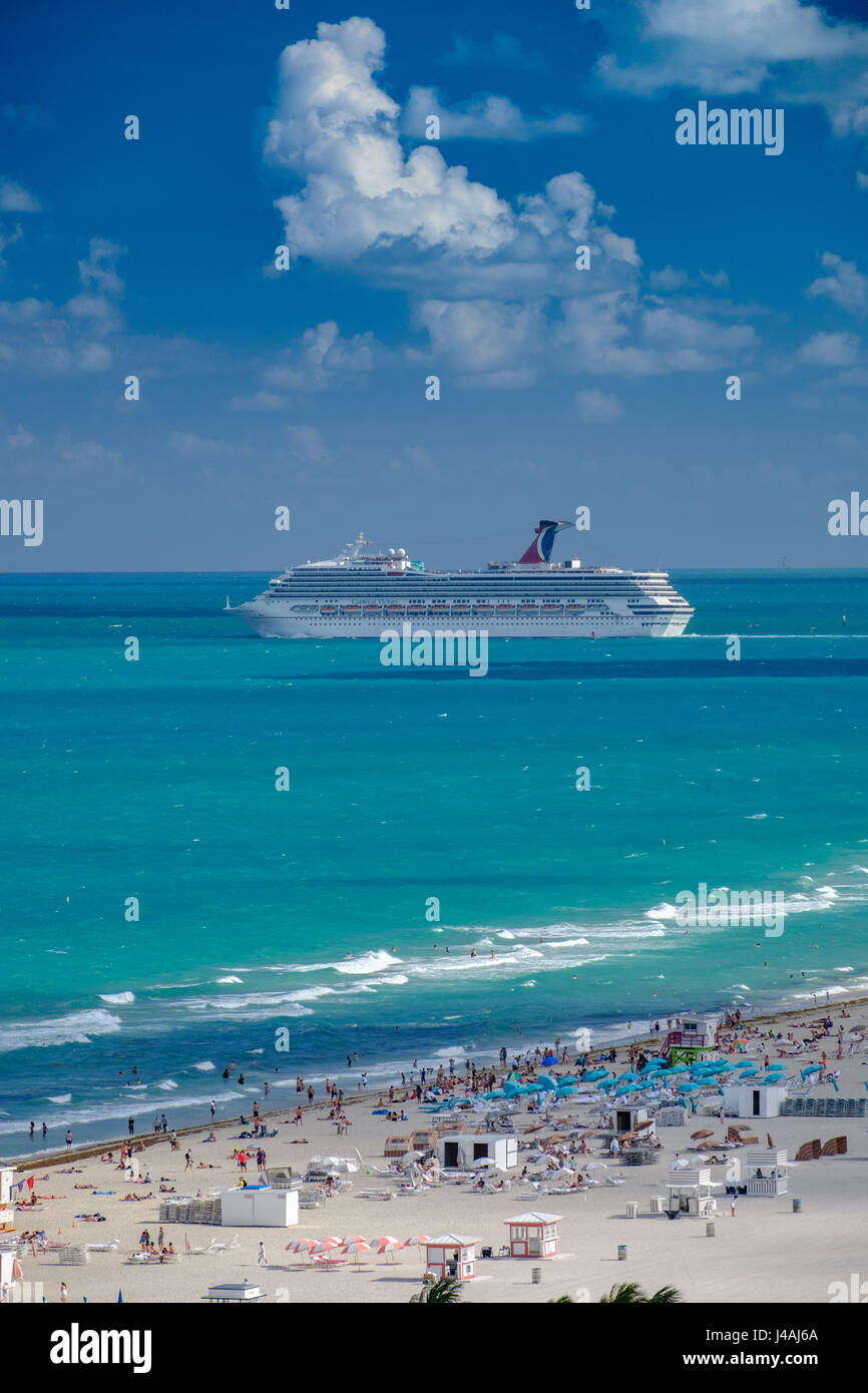 Cruise ship going out to sea with a crowded beach in the foreground ...