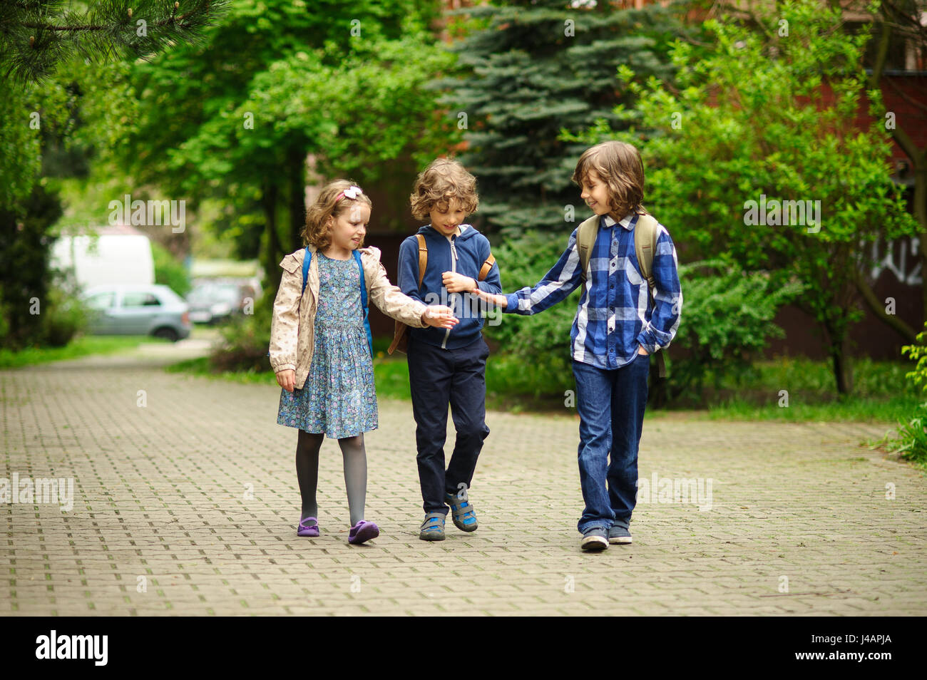 Three little friends go to school. Behind shoulders at children ...