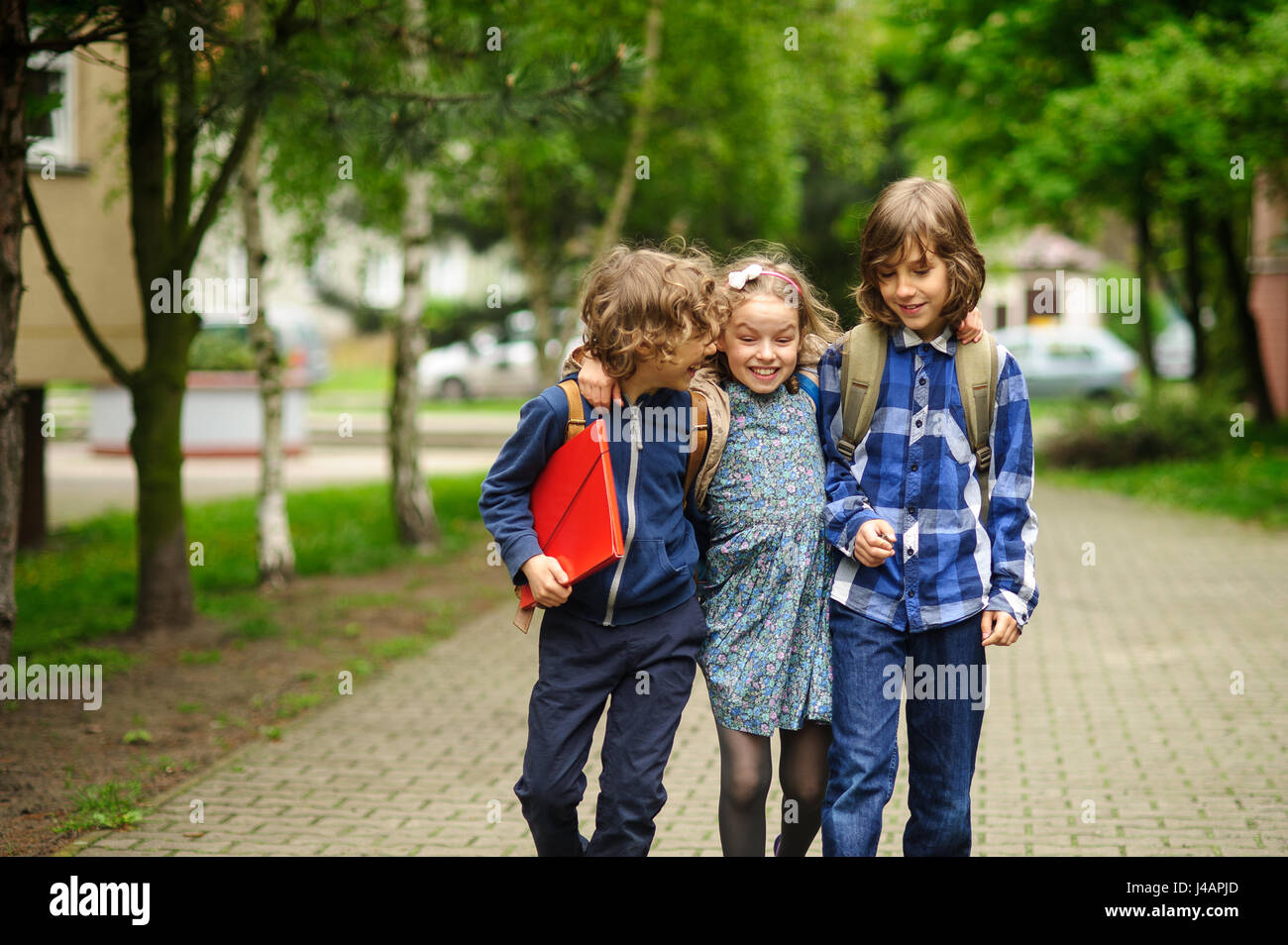 Three little friends go to school. Behind shoulders at children ...