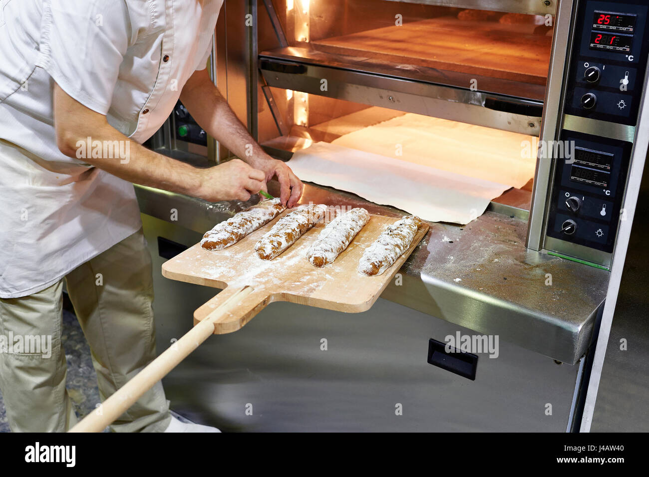 Baker prepares bread for baking in oven Stock Photo - Alamy