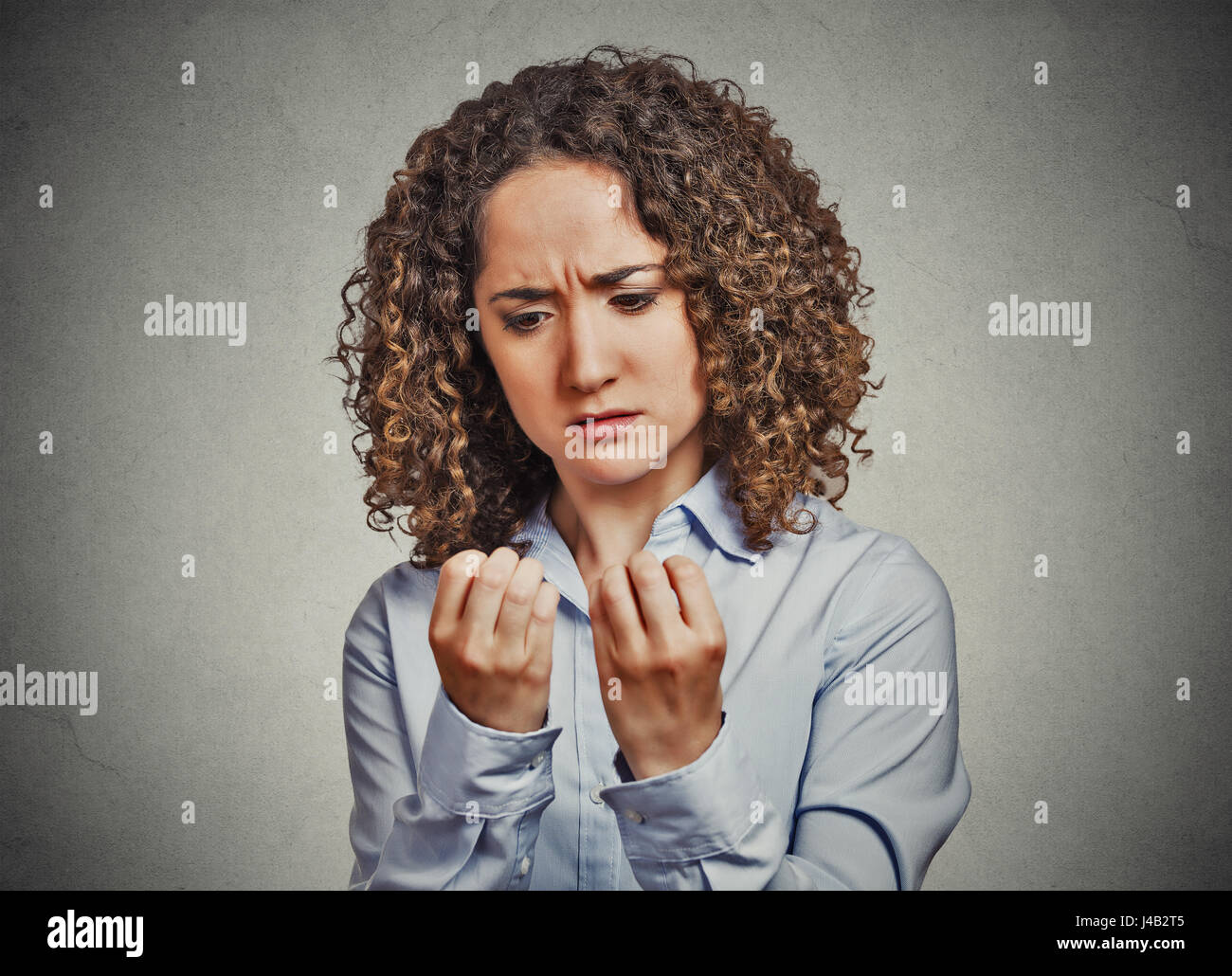 Closeup portrait worried woman looking at hands fingers nails obsessing ...