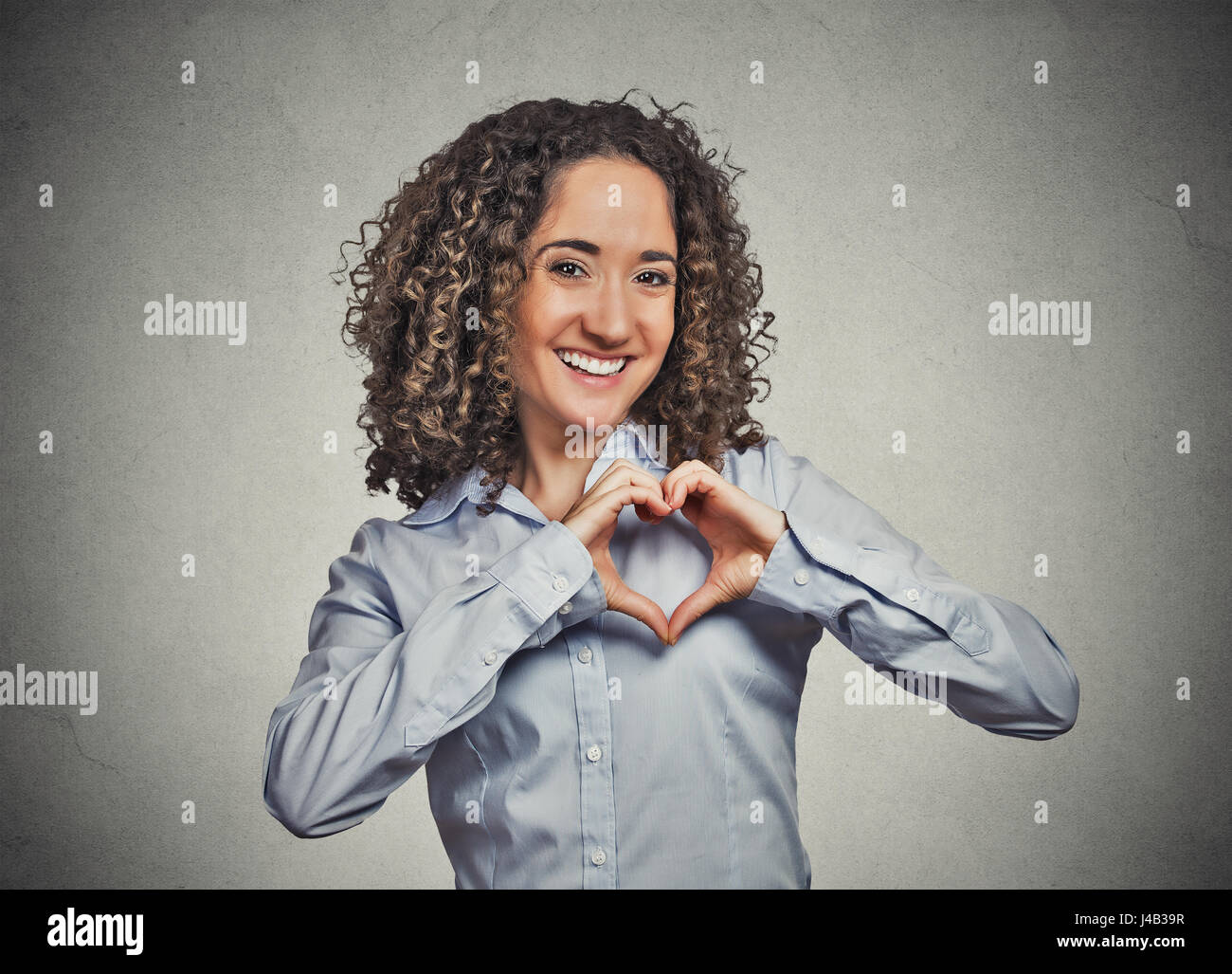 Closeup portrait smiling cheerful happy young woman making heart sign ...