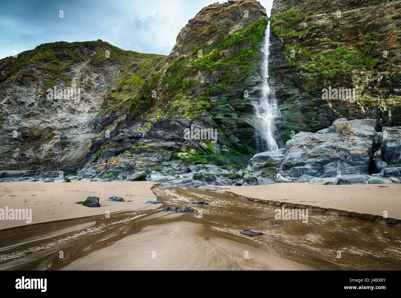 Waterfall of the River Saith flows over cliffs on the beach at Tresaith ...