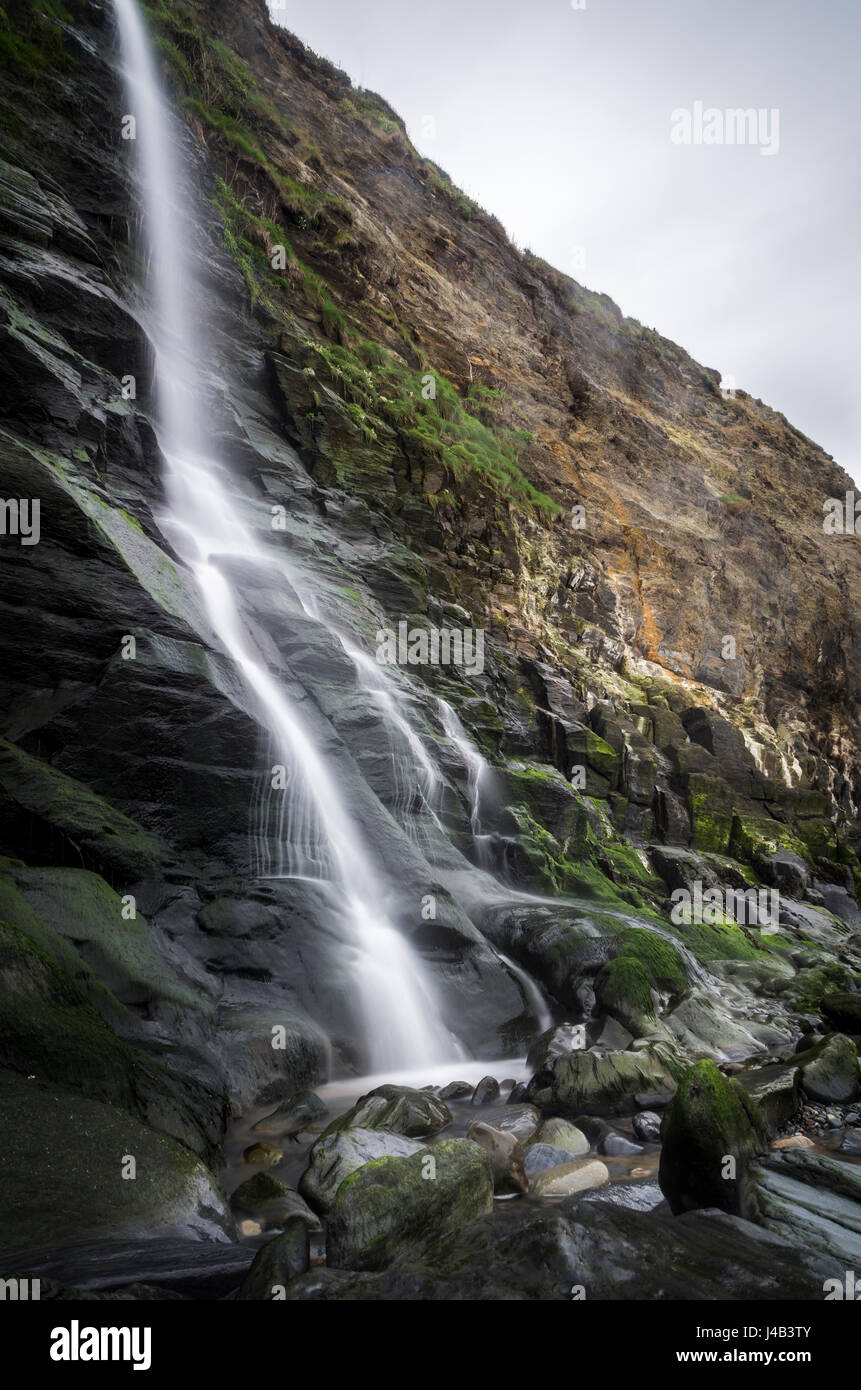 Waterfall of the River Saith flows over cliffs on the beach at Tresaith ...