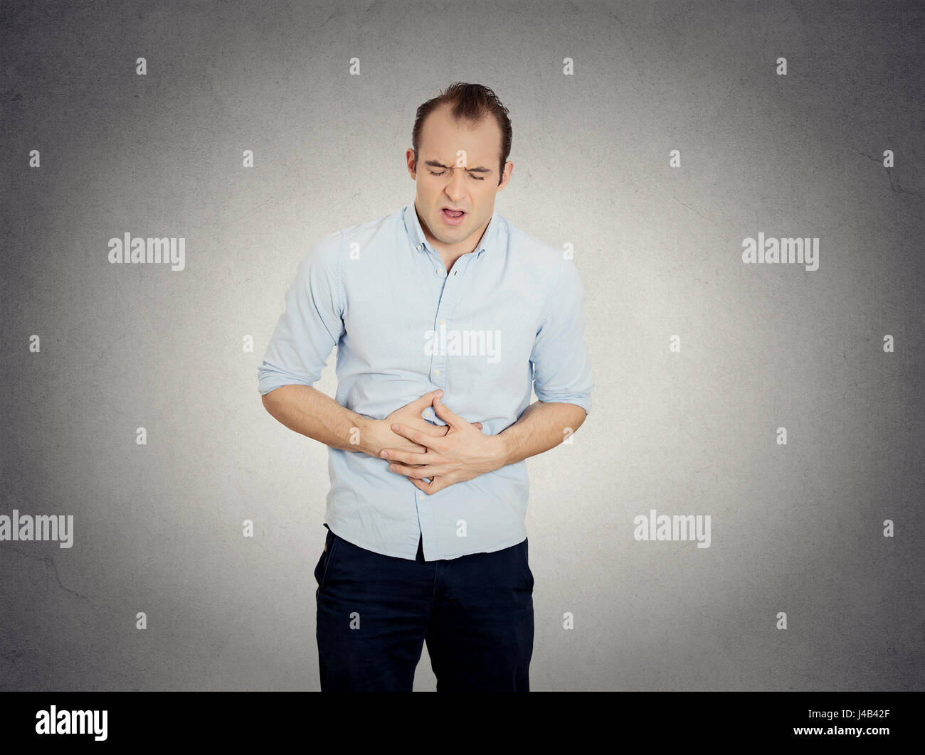 Closeup portrait miserable upset young man, doubling over in acute body ...