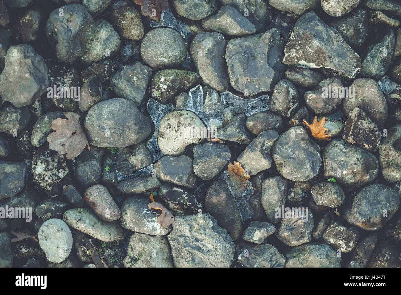 Rocks in a pile in the winter with ice and leaves between the pebbles ...
