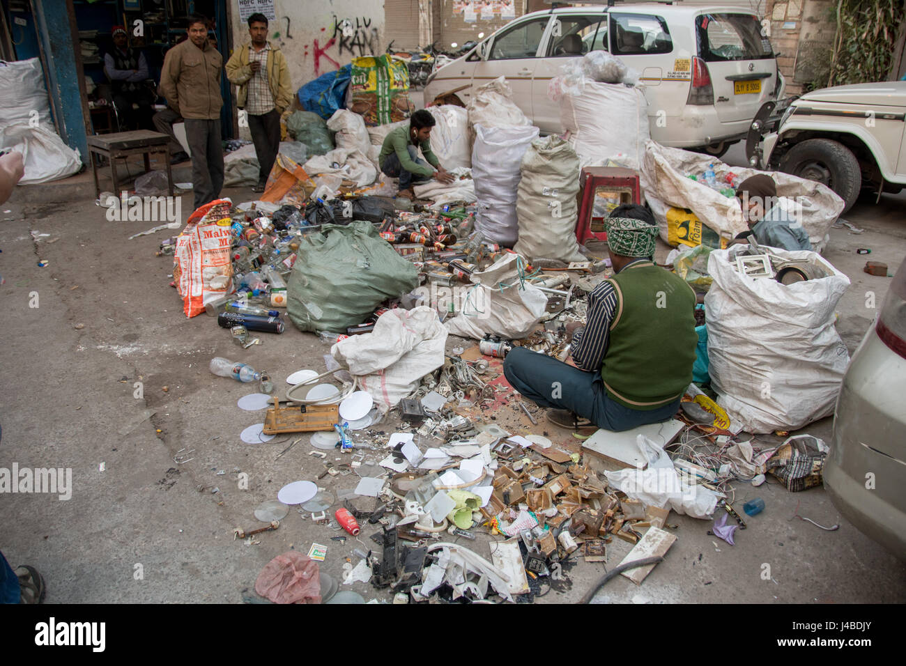 Men sit and pick through garbage and recyclable items on the street at ...