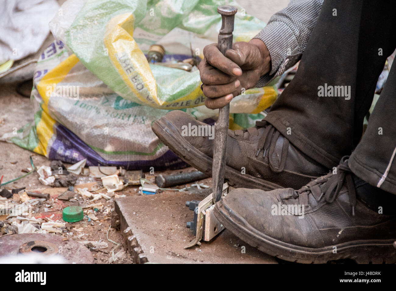 Man attempting to pick apart a electronic piece with a chisel to ...