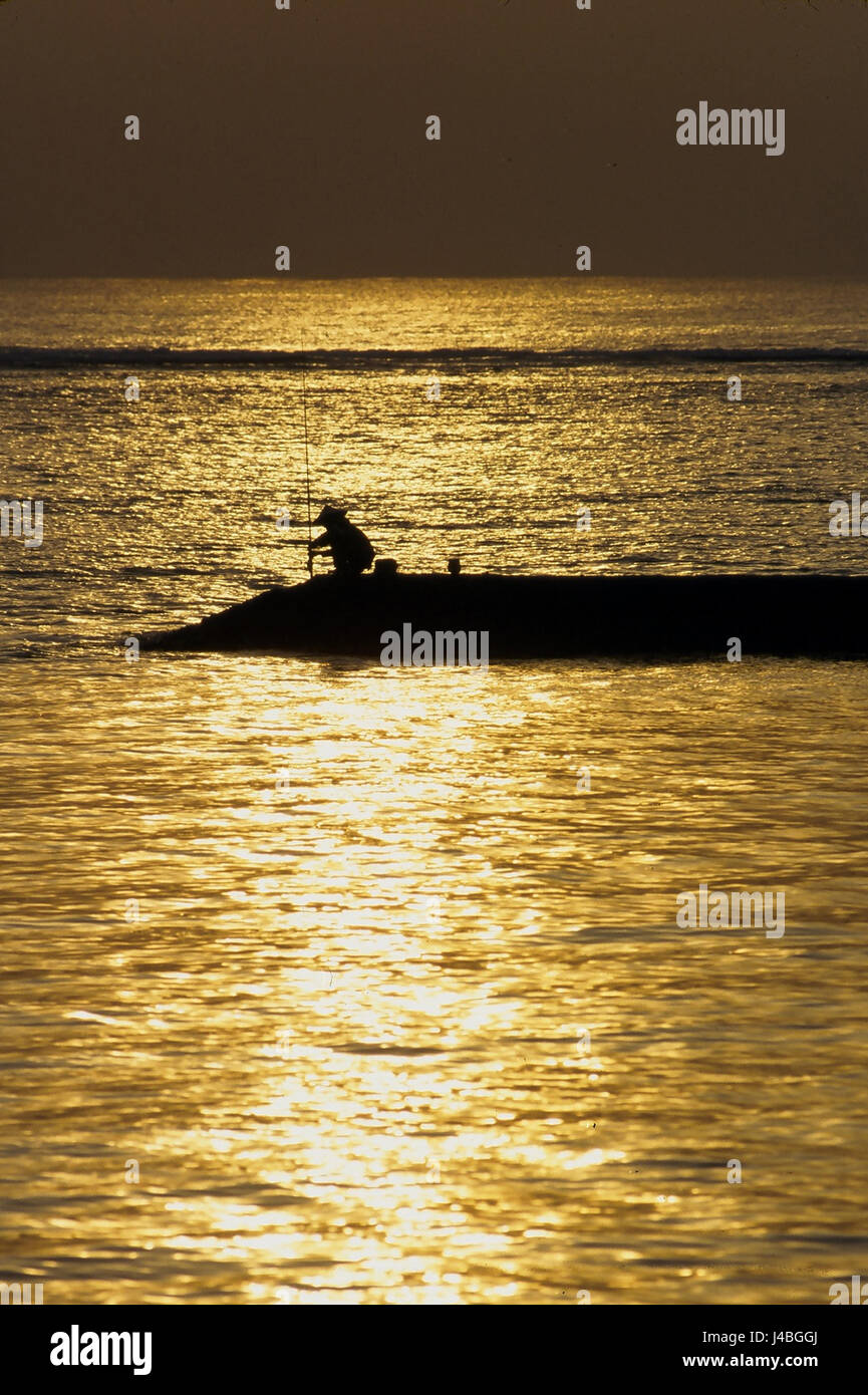 Lone fisherman fishing off a rock jetty in Sanur, Bali, Indonesia Stock ...
