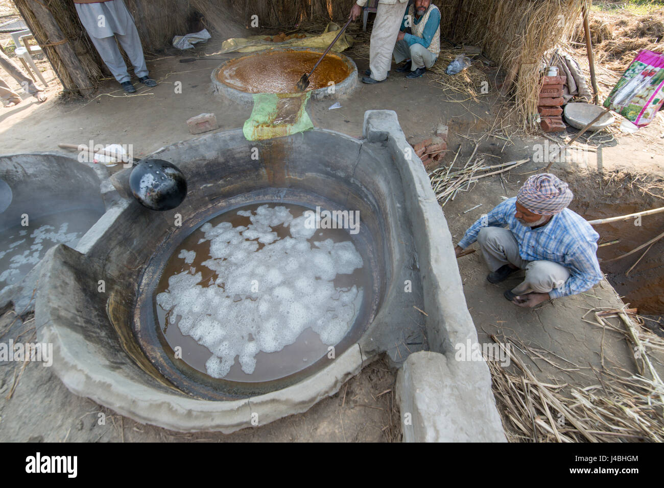 A worker is preparing to start a new batch of jaggery (traditional cane ...
