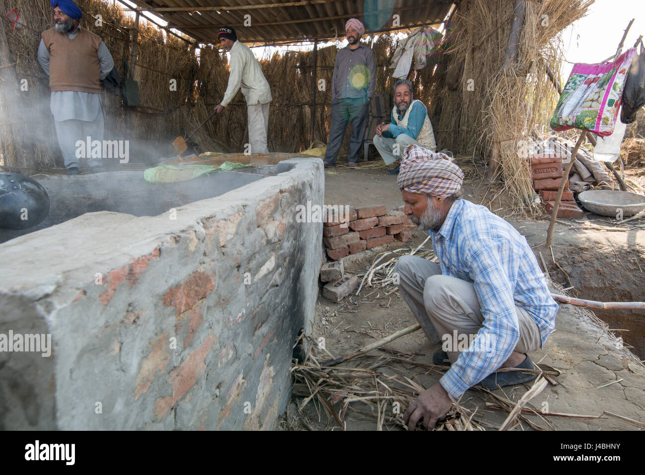 A worker is preparing to start a new batch of jaggery (traditional cane ...