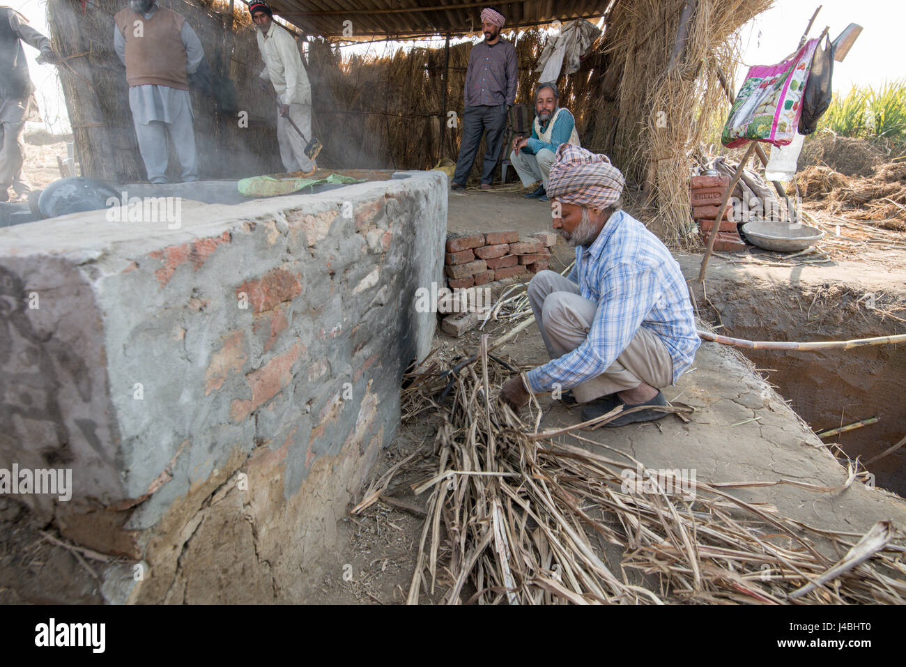 A worker is preparing to start a new batch of jaggery (traditional cane ...