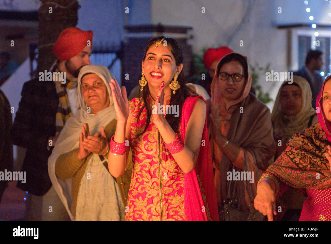 A woman dressed in traditional Indian garb dances and claps around the ...