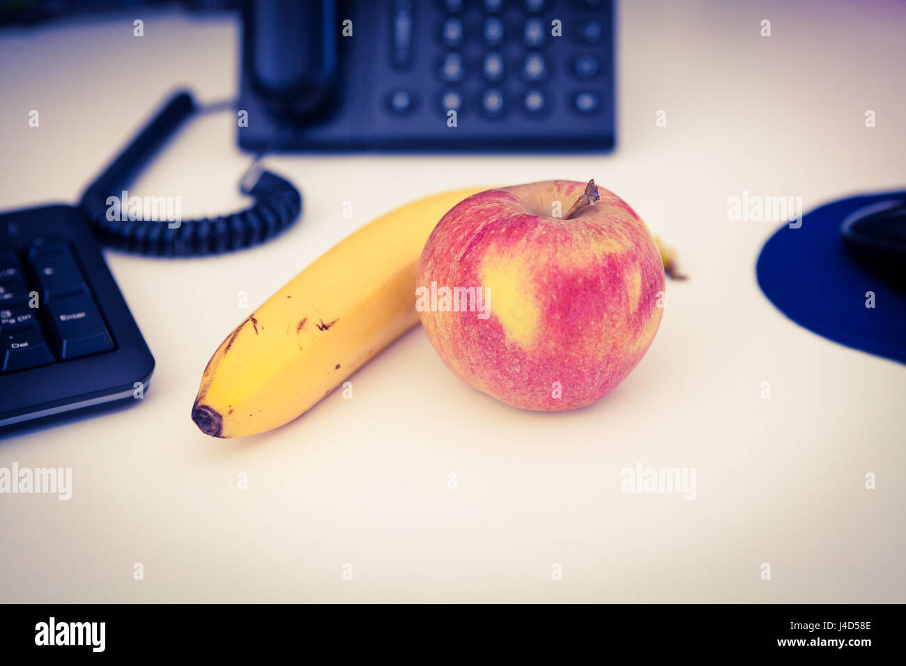 Healthy eating at work, apple and banana on the desk, yellow and purple ...