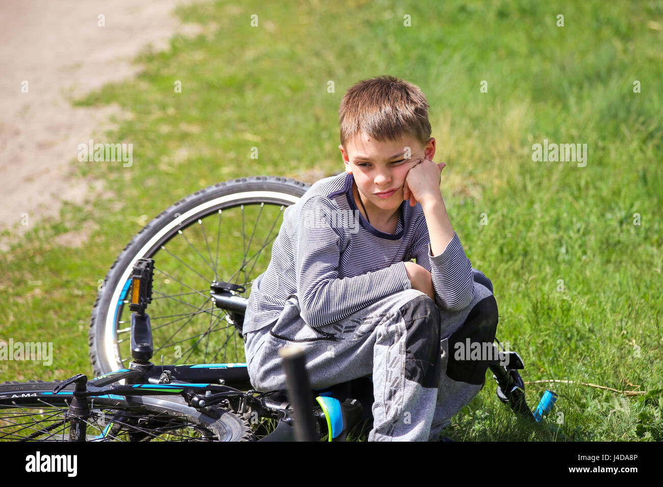 An upset boy sitting on a broken bike Stock Photo - Alamy
