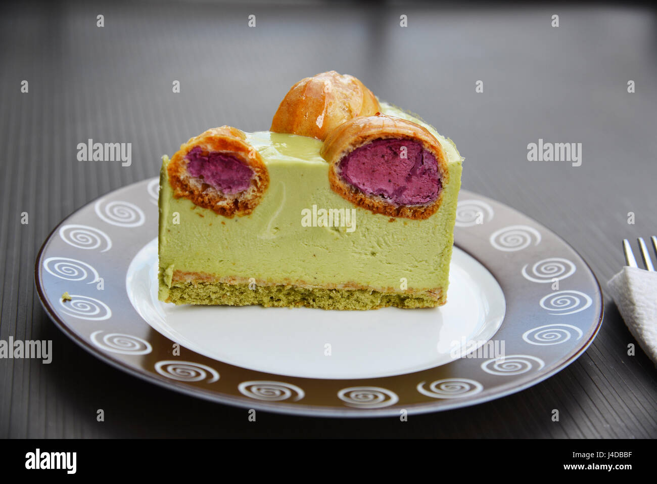 Piece of pistachio cake with a profitroles Stock Photo - Alamy