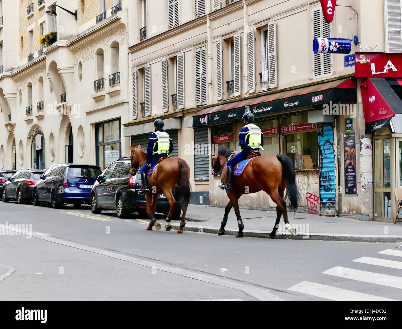 Two gendarmes, armed police, riding horses up the street on patrol, rue ...