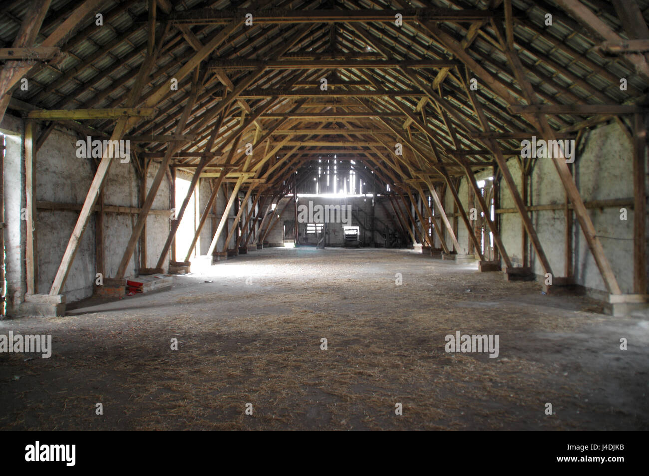 Empty rural barn with wooden supports and remains of hay on the floor ...