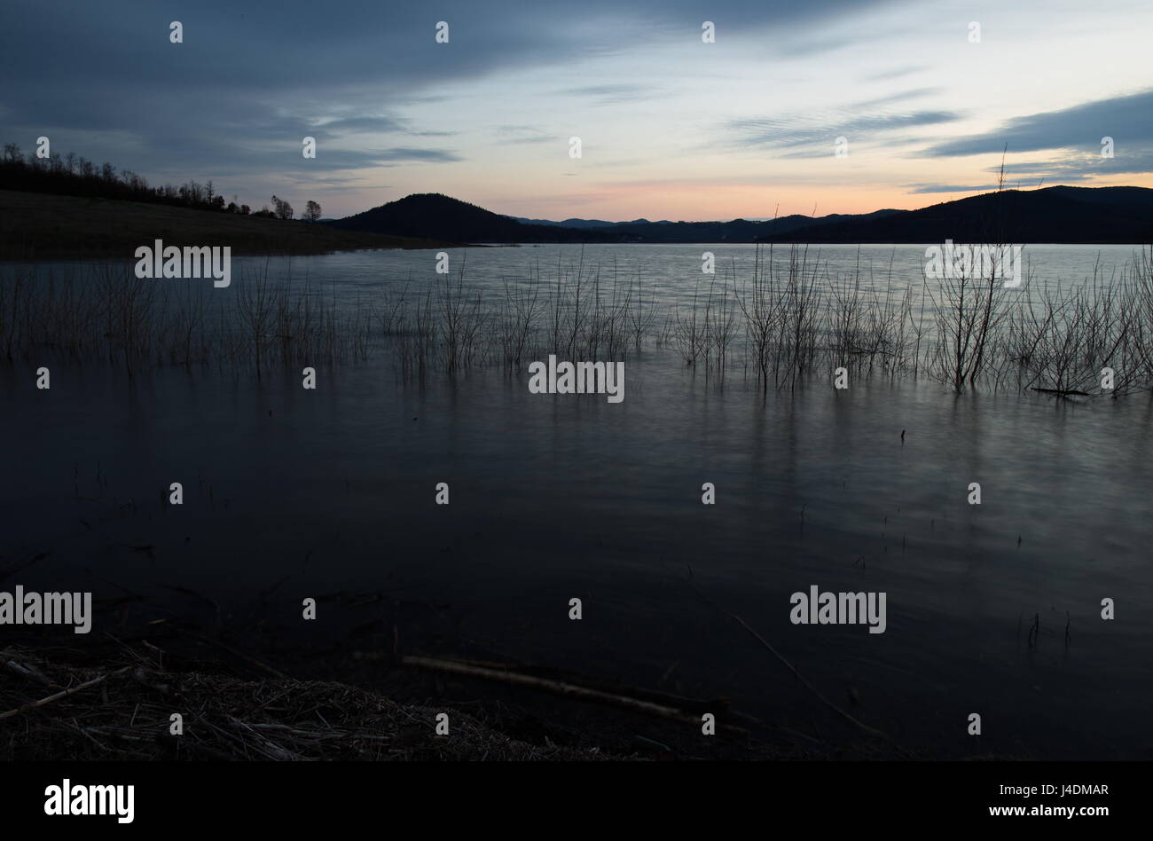 Beautiful image of a lake at dusk, with soft colors and dark shadows ...