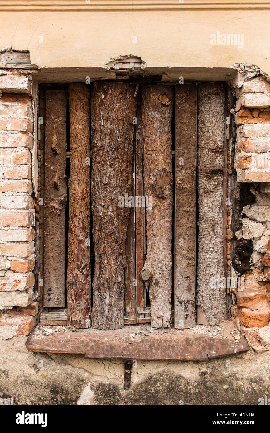 The window of the ruined house closed with wooden boards. The plaster ...