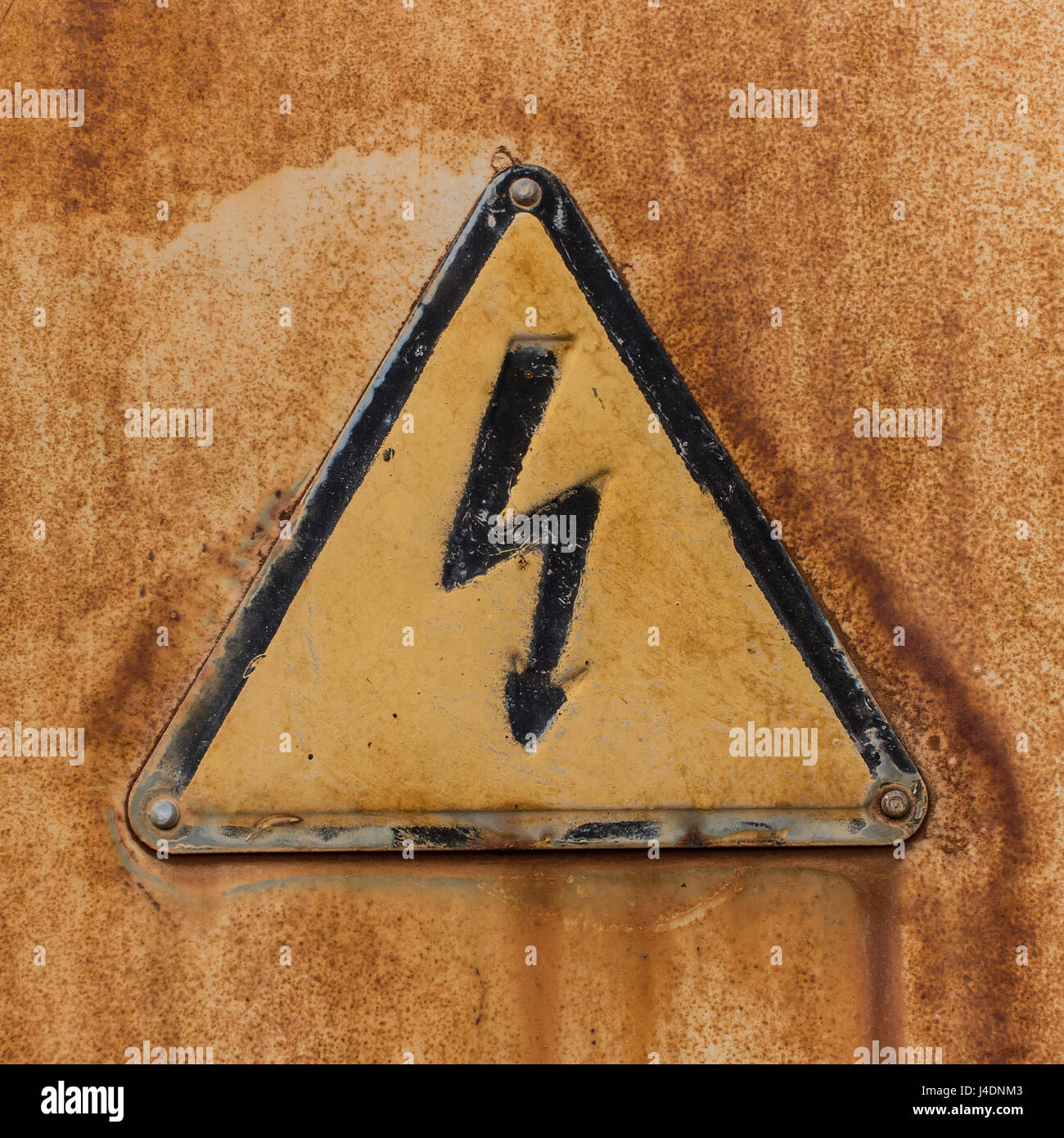 Old triangular High Voltage sign attached by rivets to a sheet of rusty ...