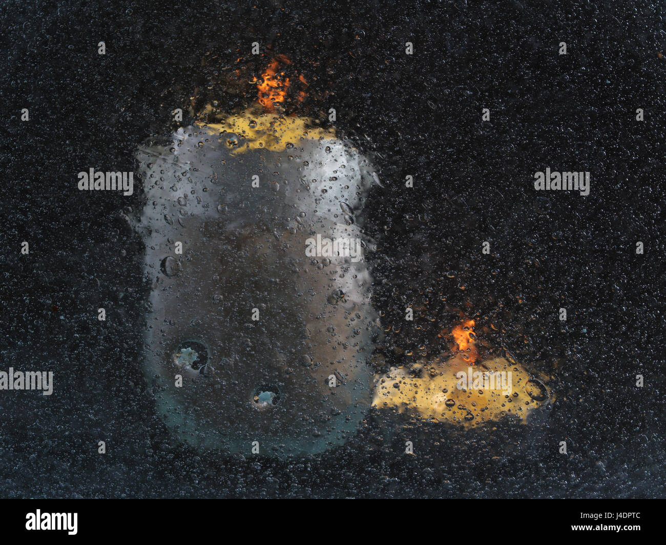 Two candles, shot through a glass with air bubbles: vague silhouettes ...