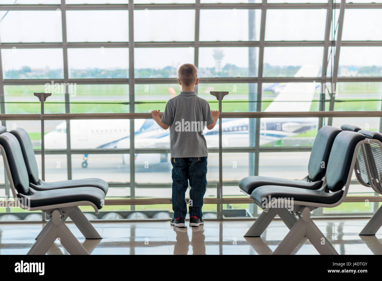 Child 7 years at the airport looking out the window, examining the ...