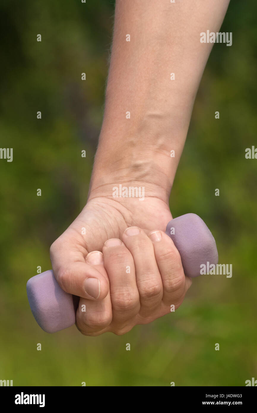 hand with dumbbell on green blurred background Stock Photo - Alamy