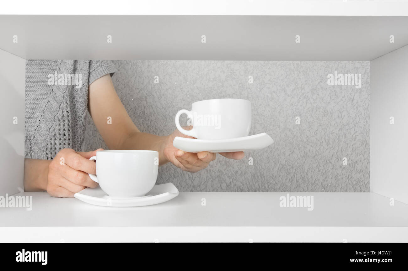 hands of woman put on the shelf white cups with saucers Stock Photo - Alamy